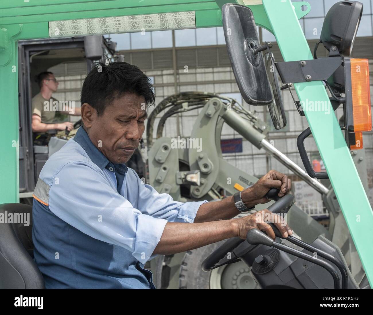 An Indonesian man drives a forklift as U.S. Staff Sgt Raymond Haynes ...