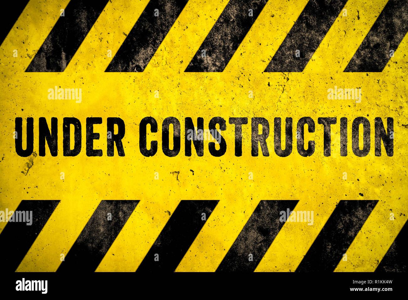 Under construction warning sign text with yellow black stripes painted ...