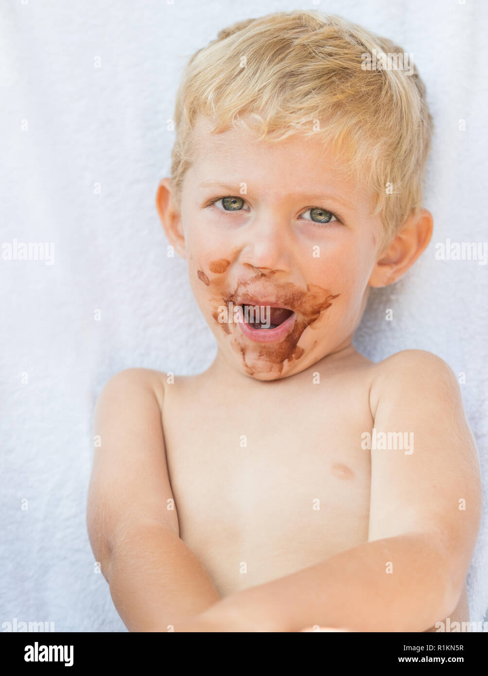 Portrait of fair-haired boy with chocolate on his face isolated on ...