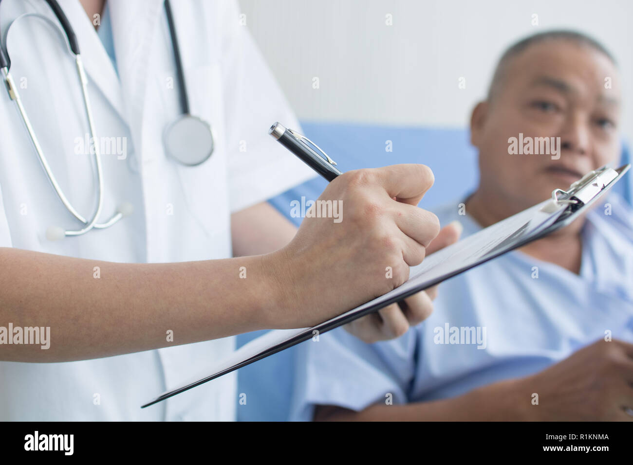 doctor writing prescription as asking old patient in hospital Stock ...