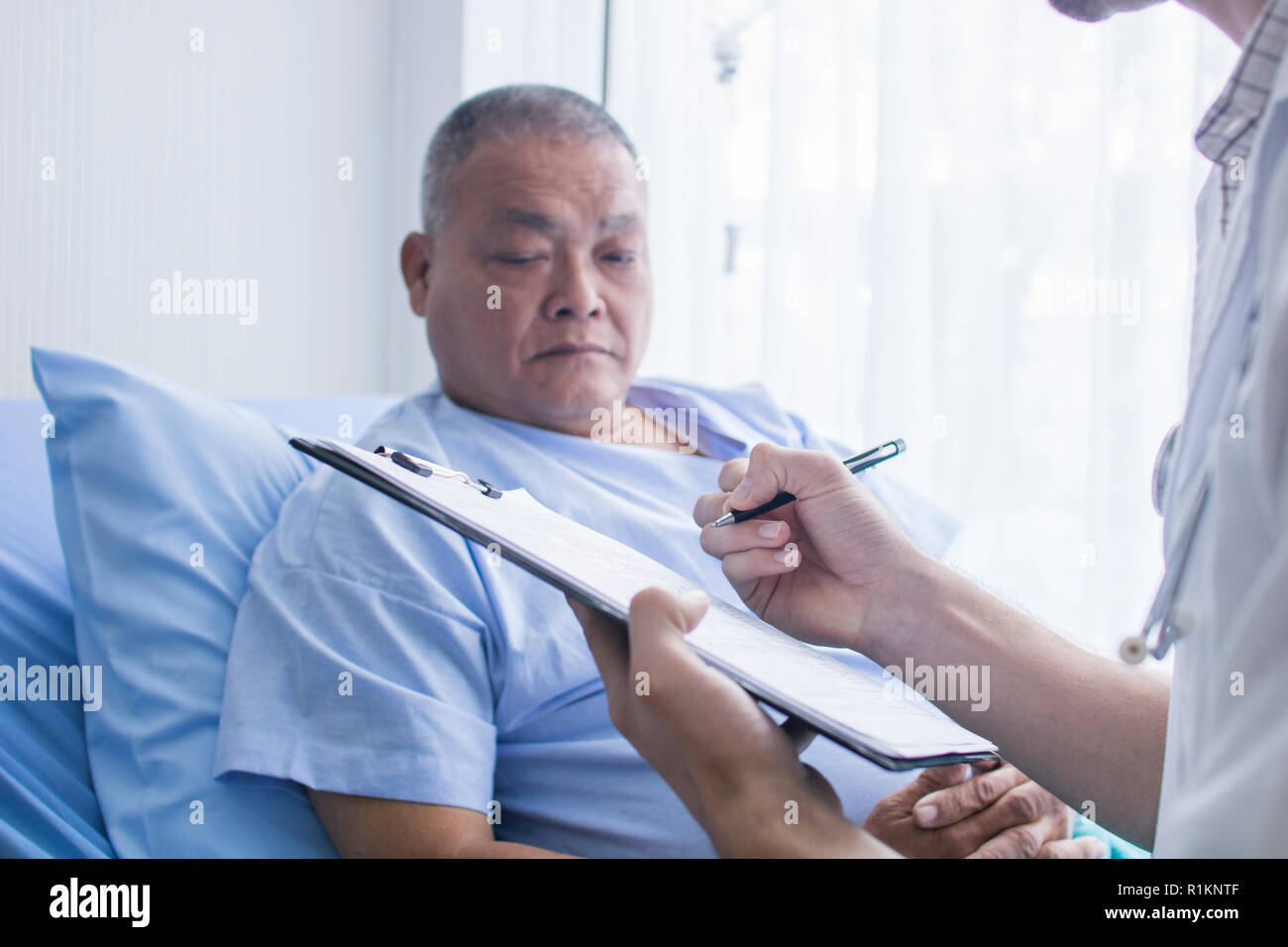 doctor filling up medical form at clipboard while standing and talking ...