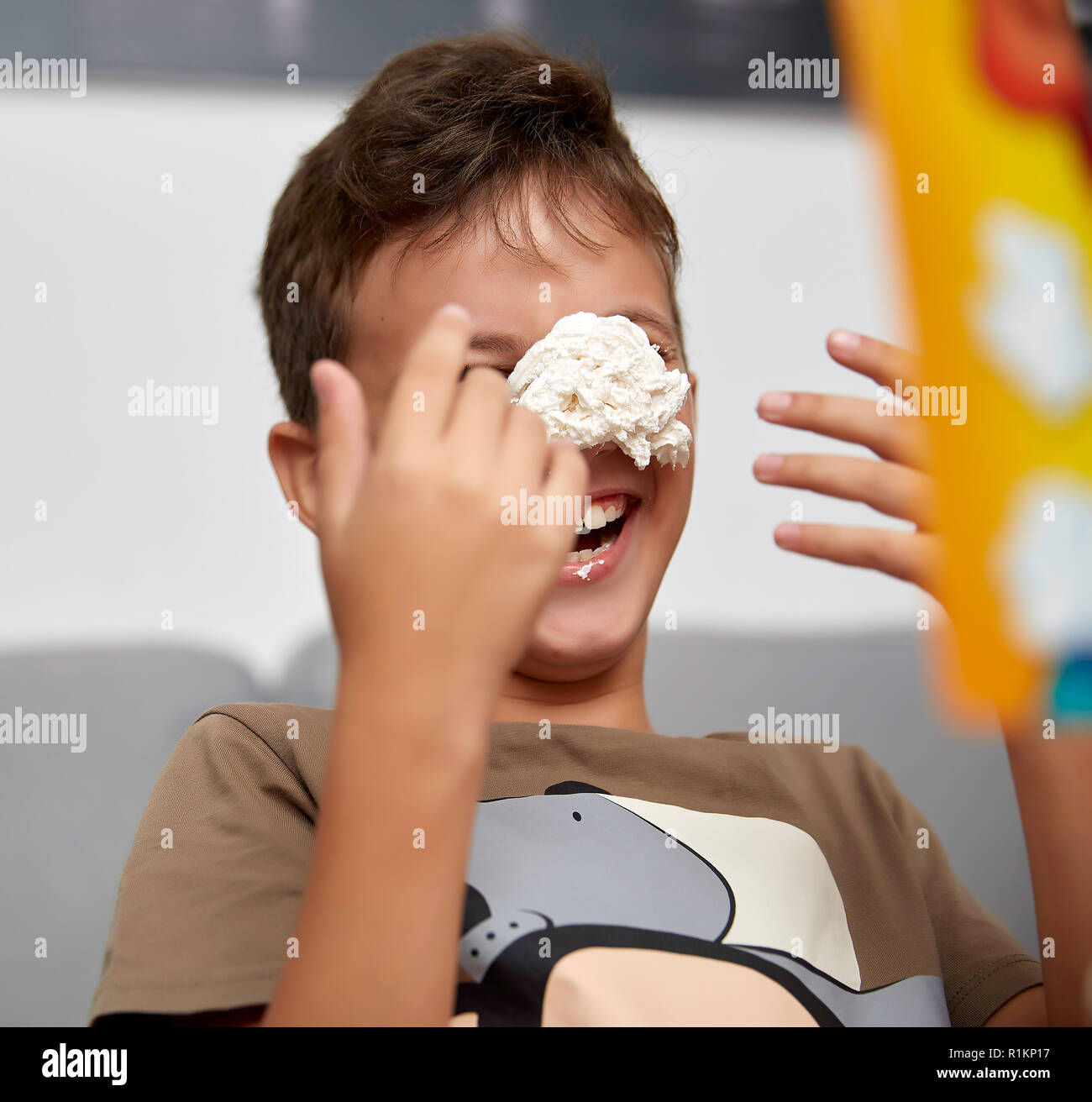 boy of ten years playing a fun game with sweet cream, cream in the face ...