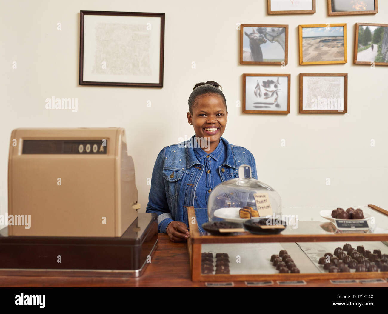 Smiling young artisanal chocolate shop owner standing behind her ...