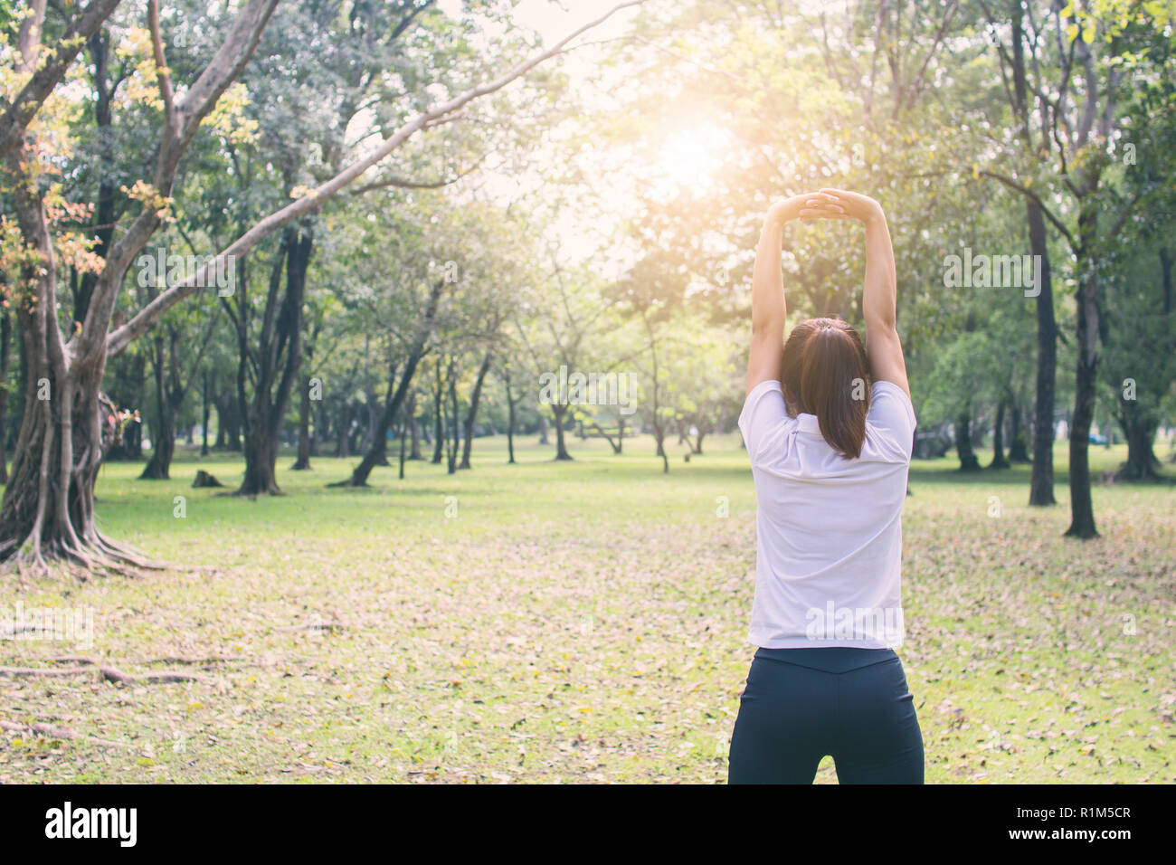 sport runner worm up and exercise before running, woman workout in park ...