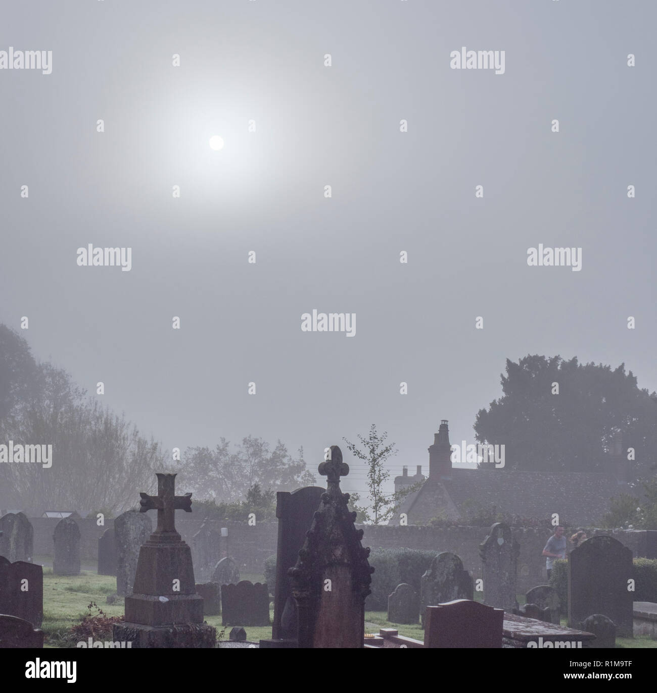 Sun beginning to break through the grey mist at a Church Graveyard ...