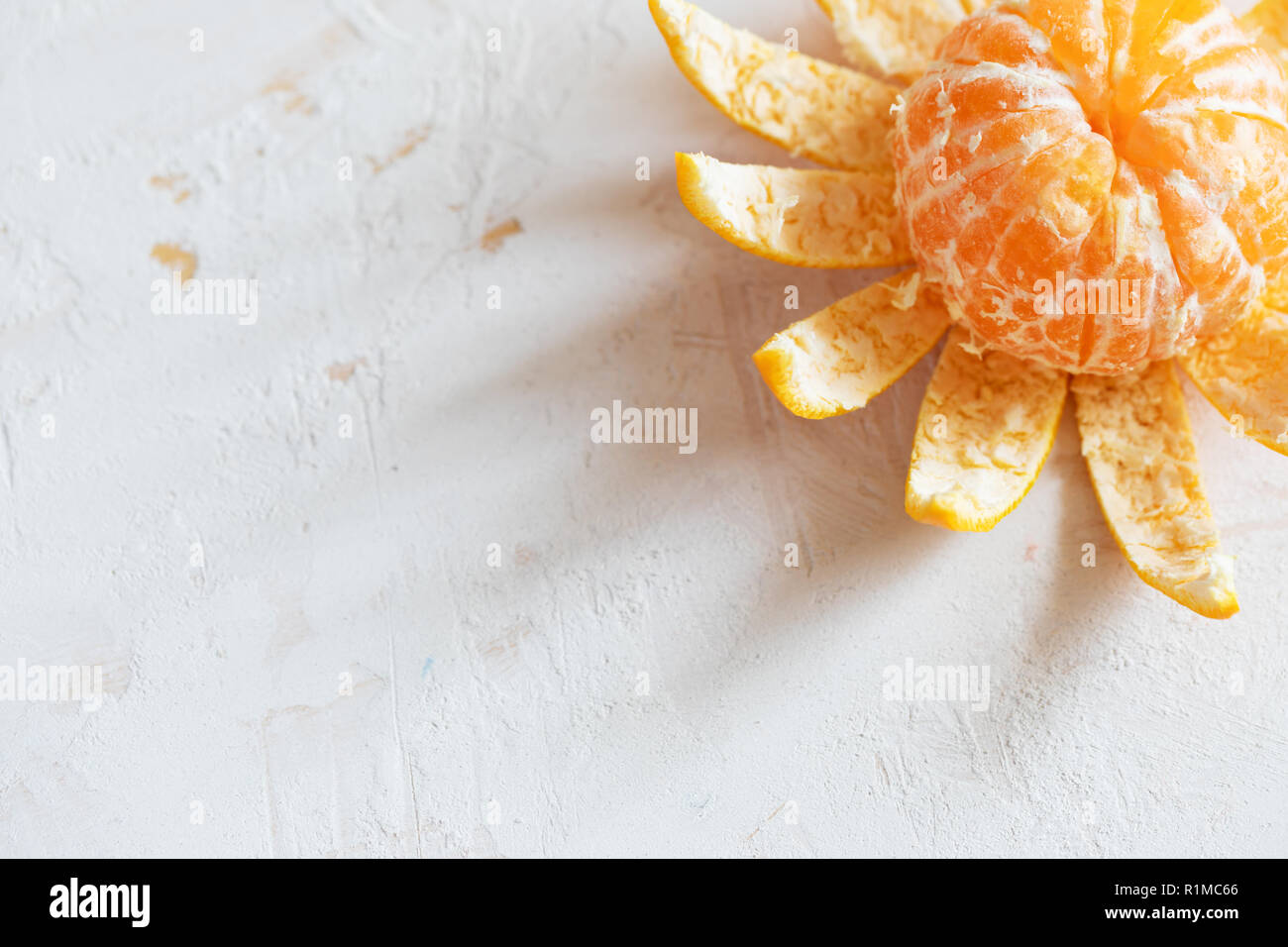 Close-up fresh orange peeled mandarin with peel like flower or sun on ...