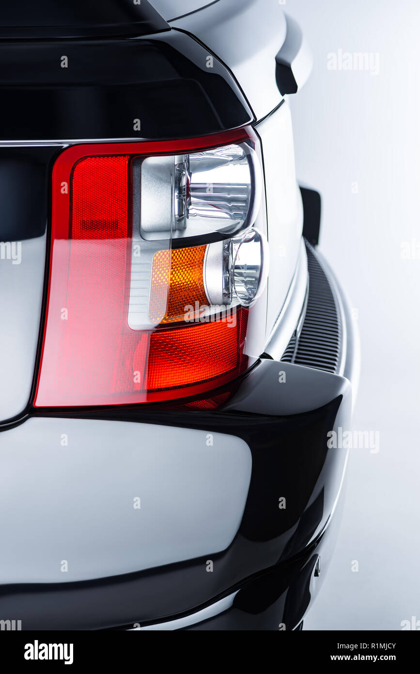 Close up view of rear headlight of luxury black car on grey backdrop ...