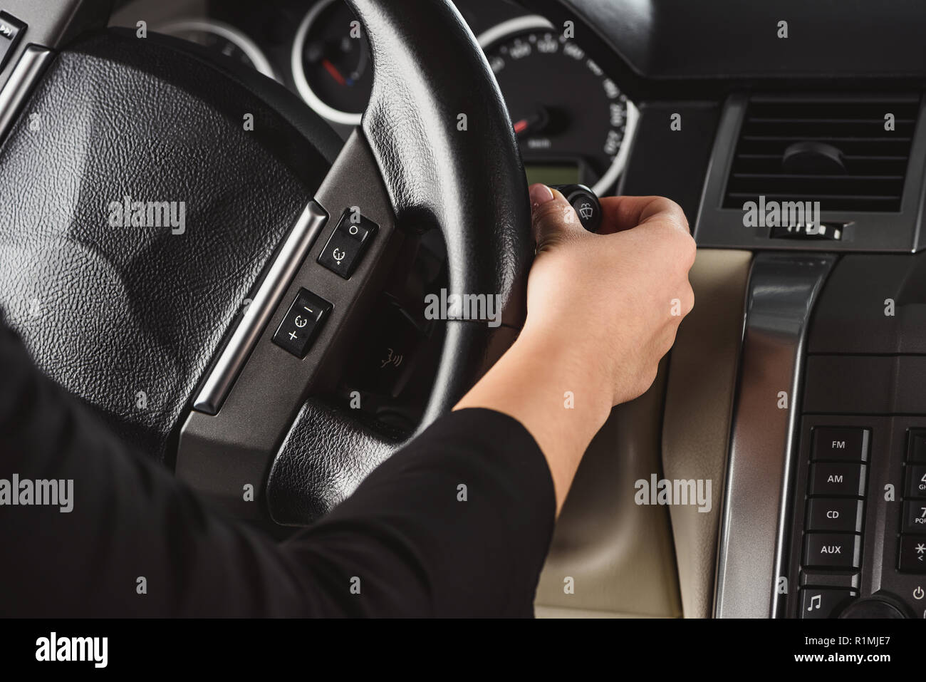 Cropped shot of woman turning on windscreen wipers while driving car ...
