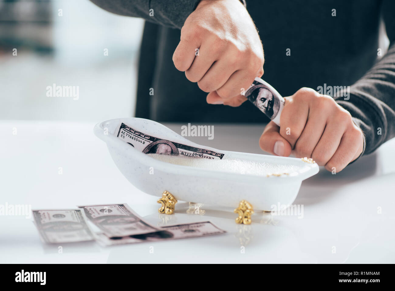 cropped shot of man washing dollars in small bathtub, money laundering ...