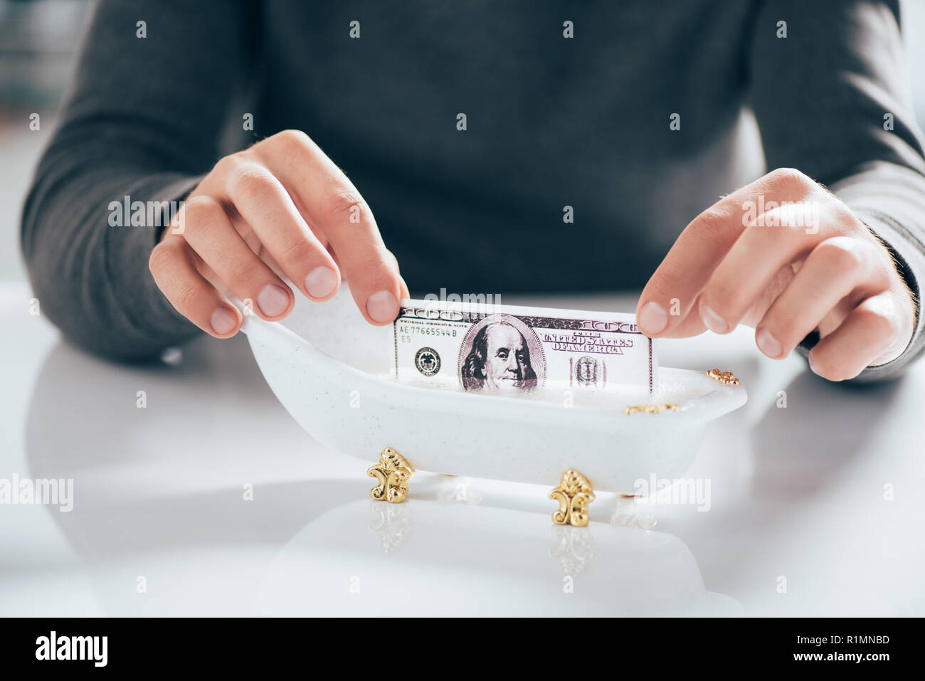 cropped shot of man washing dollar banknote in tub, money laundering ...
