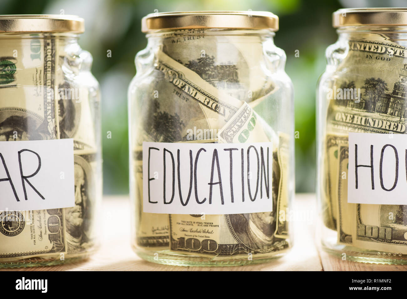 glass jars with dollar banknotes and inscriptions car, education, house ...