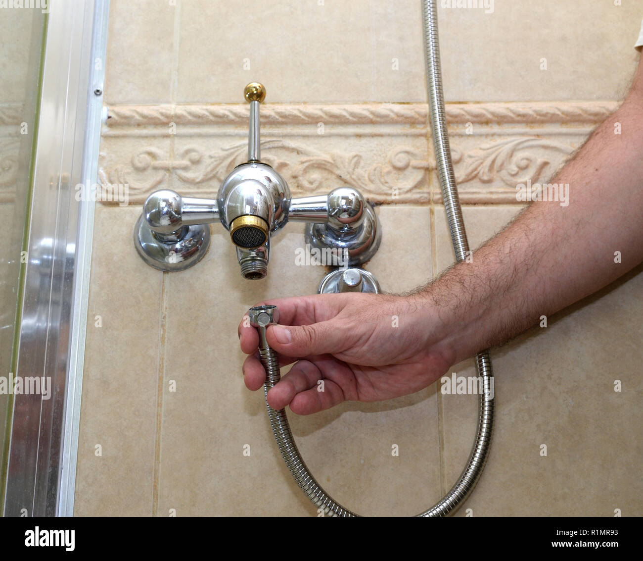 Installing a new shower hose on an used shower mixer tap in a shower ...