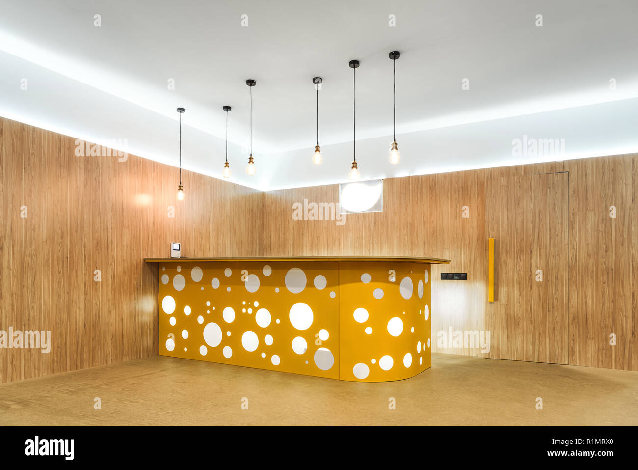 illuminated lamps and yellow reception desk in modern kindergarten ...