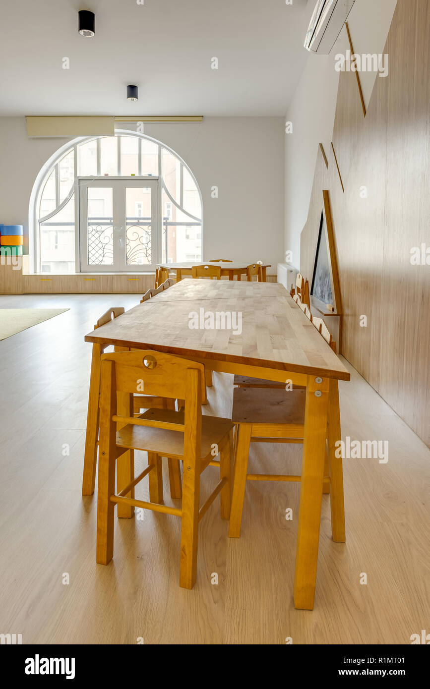 wooden tables and small chairs in modern kindergarten classroom ...