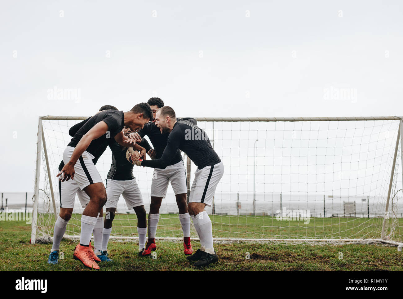 Soccer players joining hands standing in a huddle having a pep talk ...