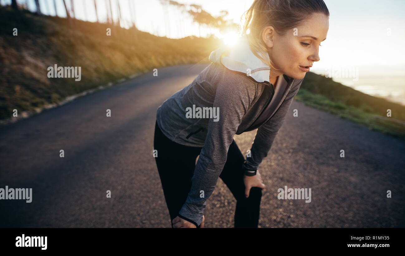 Female runner taking a break during her morning jog standing on a ...