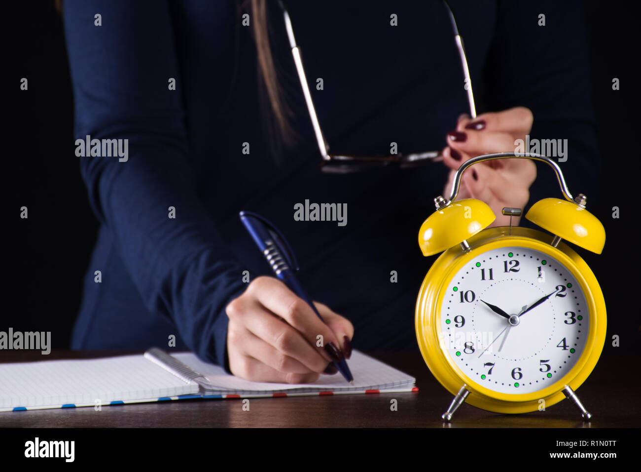 Yellow alarm old retro analog clock and girl in background writing in ...