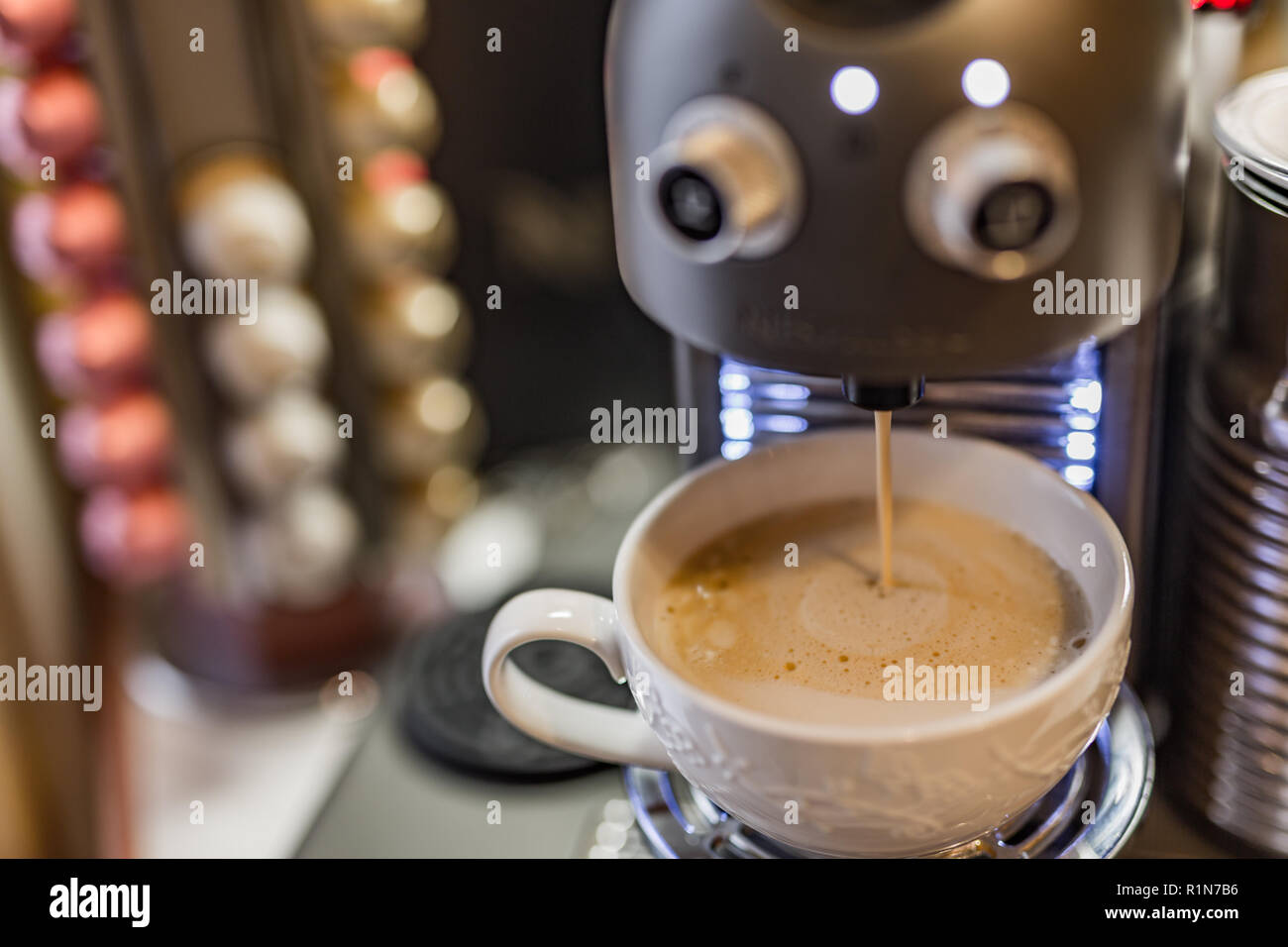 Espresso coffee capsules and machine maker on a wooden table, blur ...