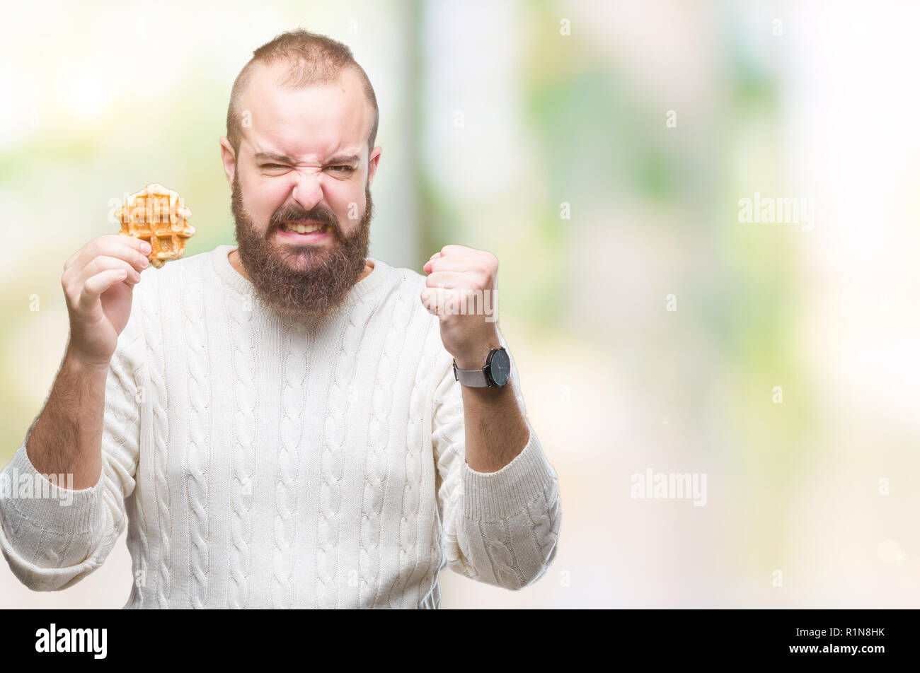 Young caucasian hipster man eating sweet waffle over isolated ...