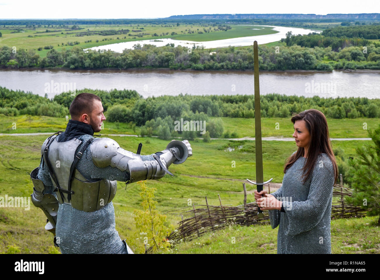 A lady in chain mail and a knight in armor learn to hold a weapon and ...