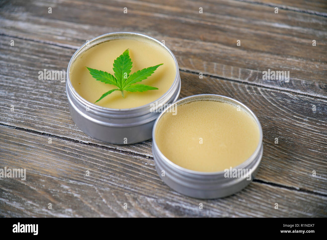 Cannabis hemp cream with marijuana leaf over wood background - cannabis ...