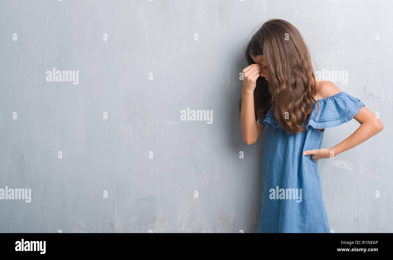Young hispanic kid over grunge grey wall tired rubbing nose and eyes ...