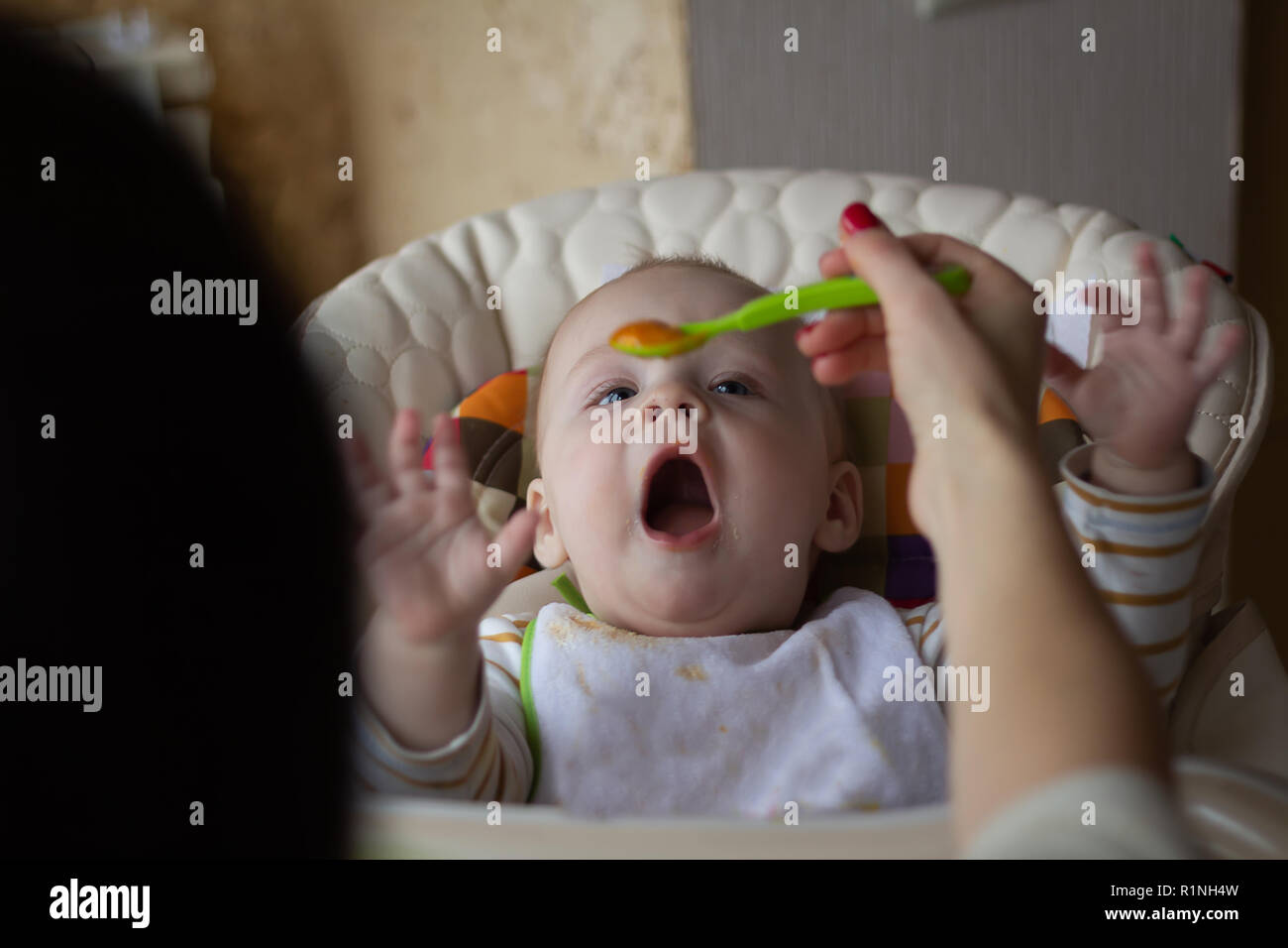 The first feeding of the baby from the spoon. Mom feeds baby ...