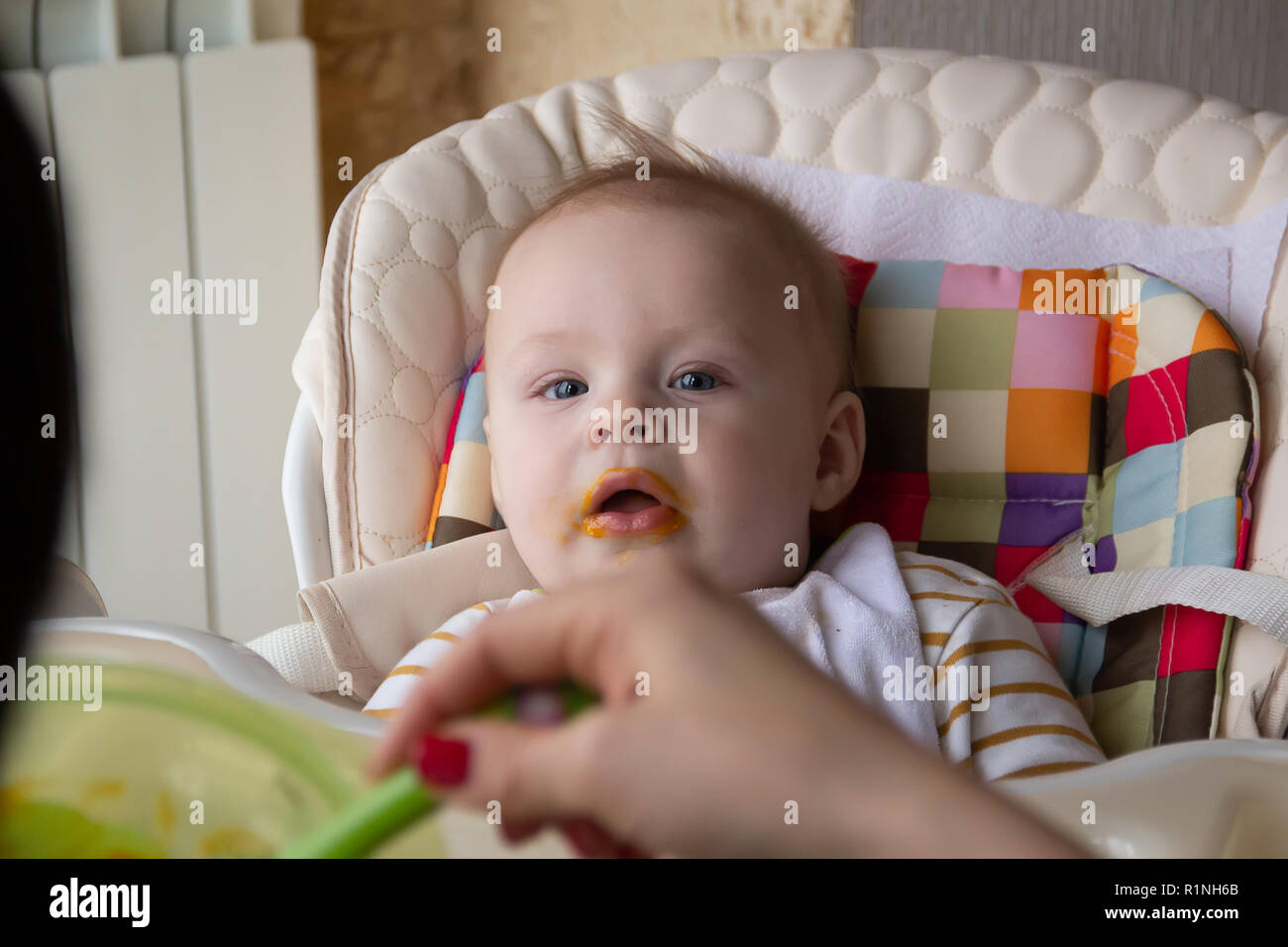 The first feeding of the baby from the spoon. Mom feeds baby ...
