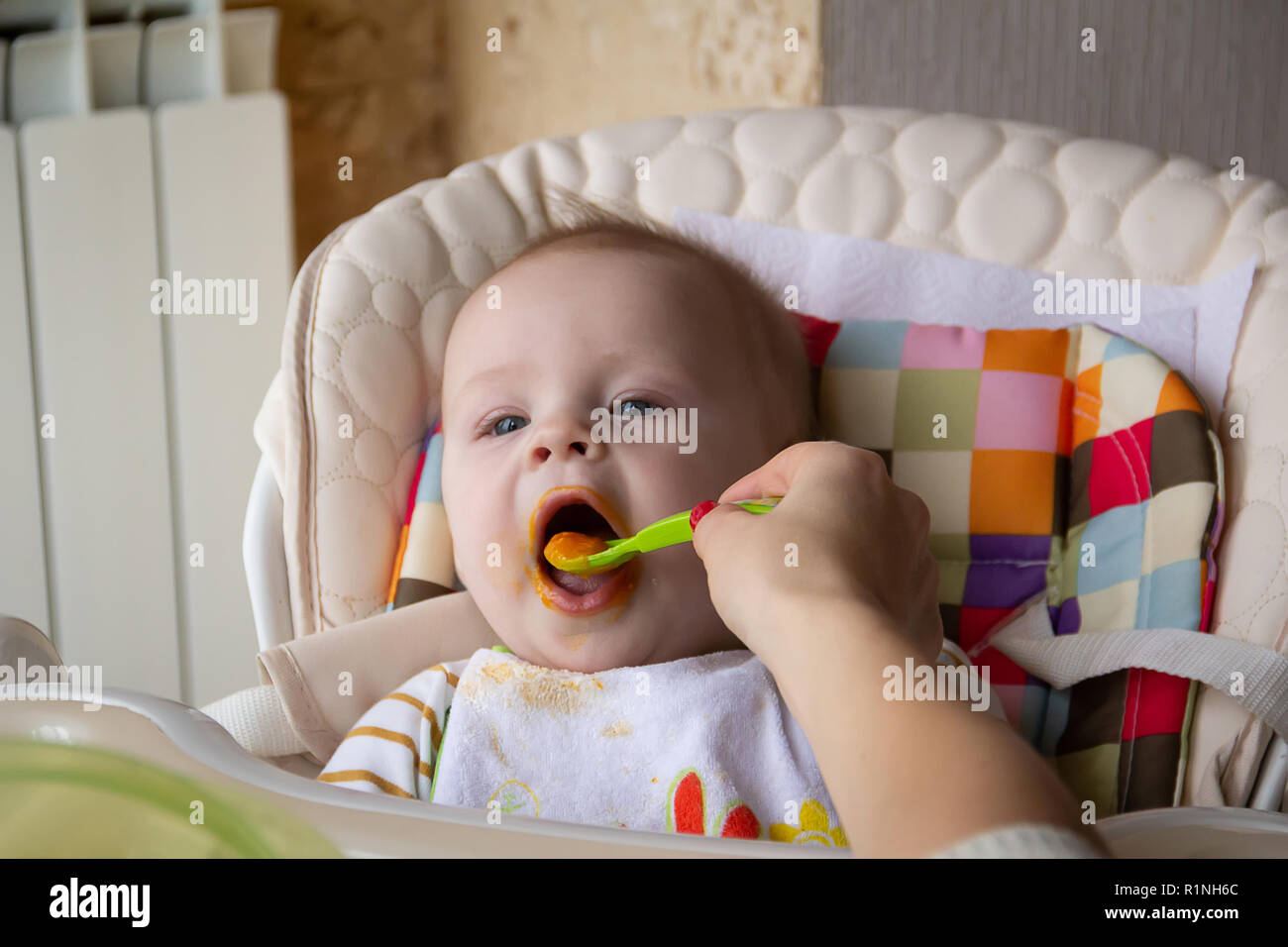 The first feeding of the baby from the spoon. Mom feeds baby ...