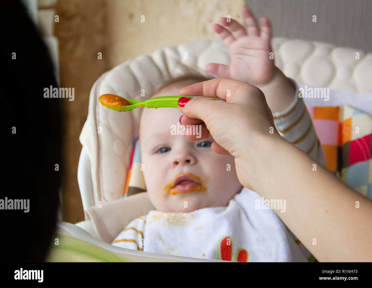 The first feeding of the baby from the spoon. Mom feeds baby ...