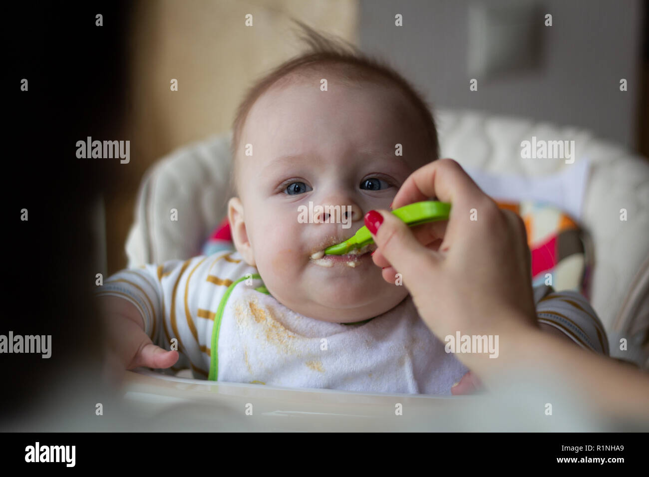 The first feeding of the baby from the spoon. Mom feeds baby ...