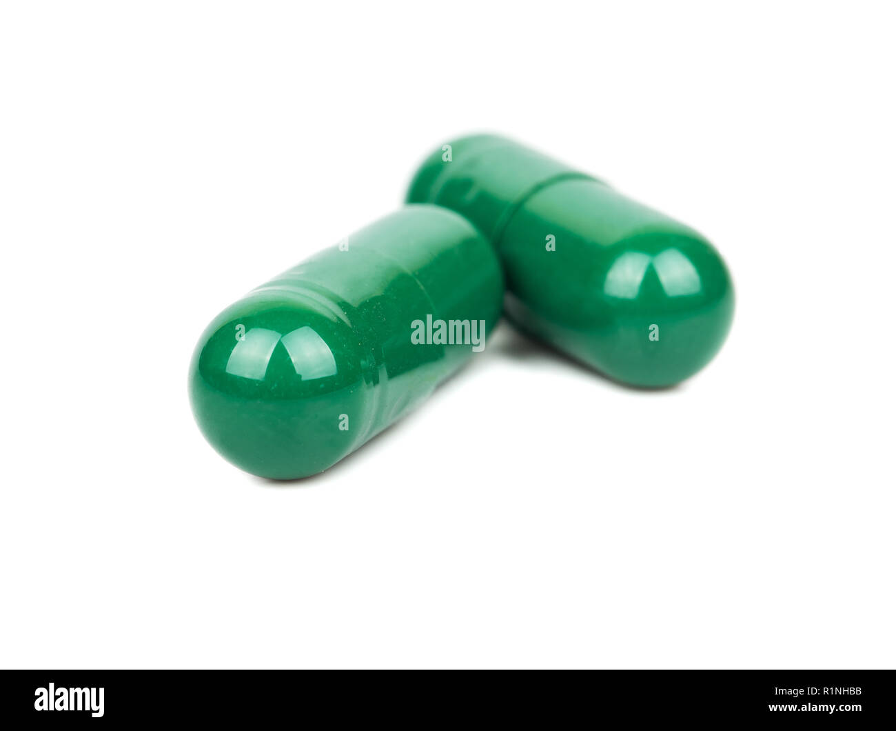 Two green herbal capsule isolated on white background Stock Photo - Alamy