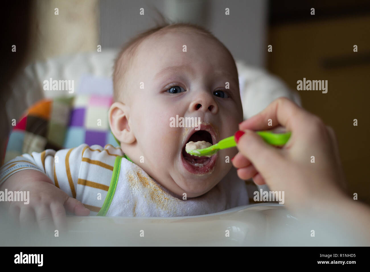 The first feeding of the baby from the spoon. Mom feeds baby ...