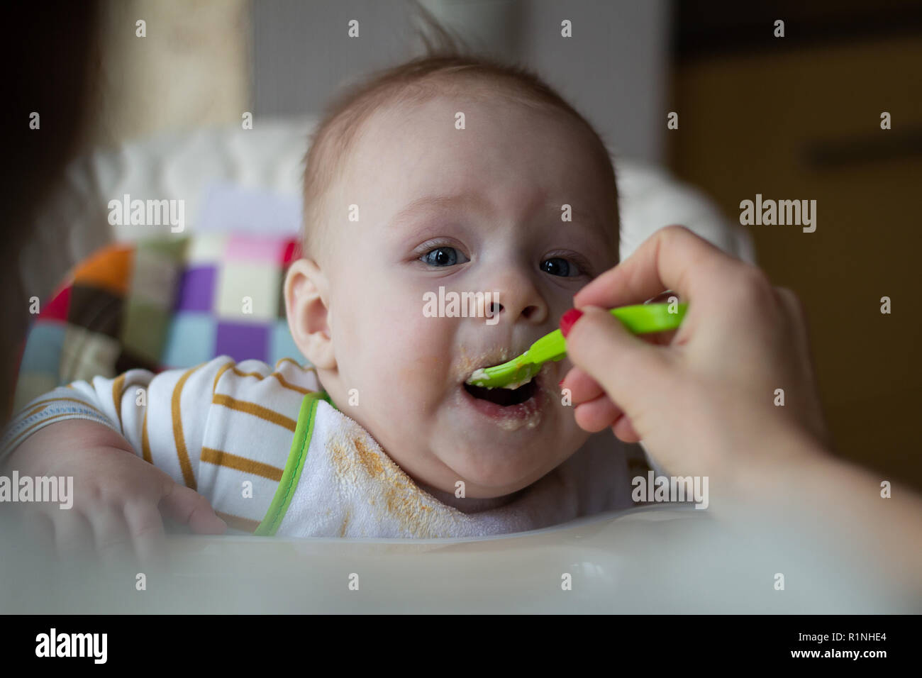 The first feeding of the baby from the spoon. Mom feeds baby ...