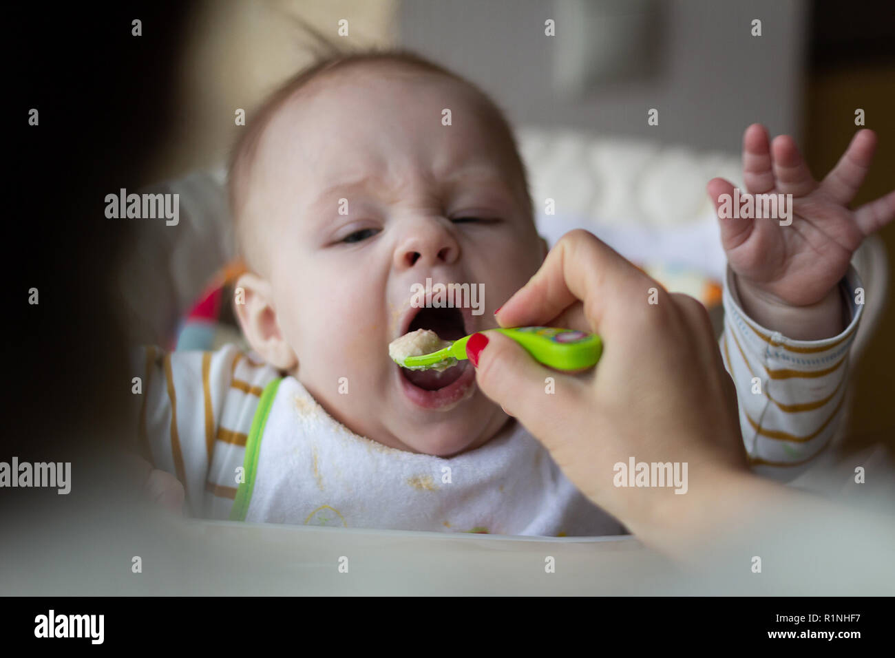 The first feeding of the baby from the spoon. Mom feeds baby ...