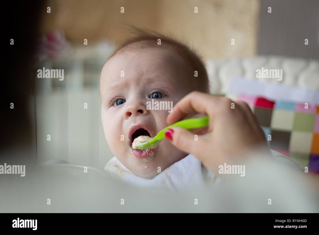 The first feeding of the baby from the spoon. Mom feeds baby ...