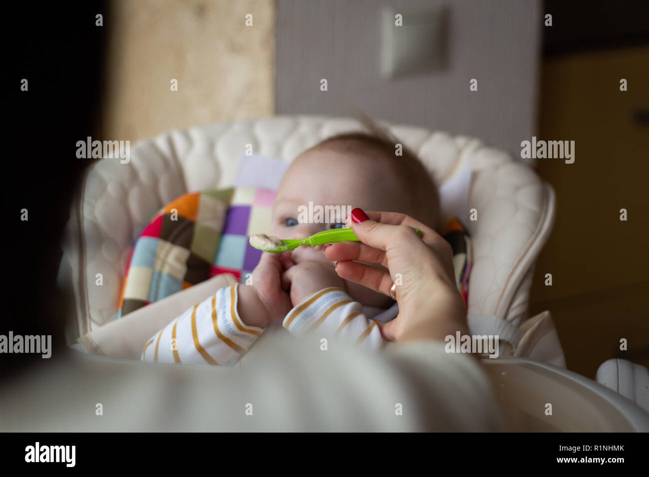 The first feeding of the baby from the spoon. Mom feeds baby ...