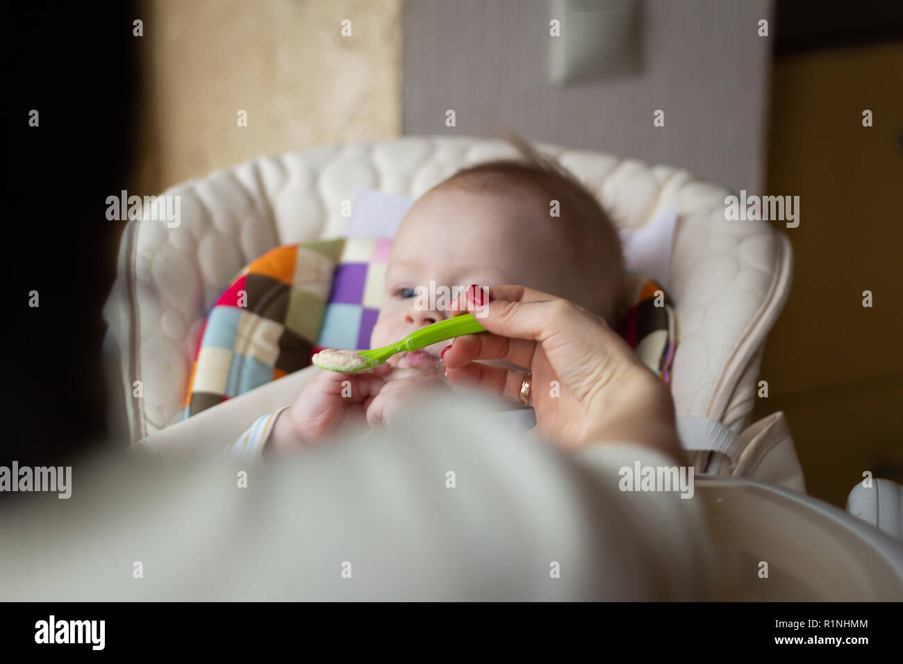 The first feeding of the baby from the spoon. Mom feeds baby ...