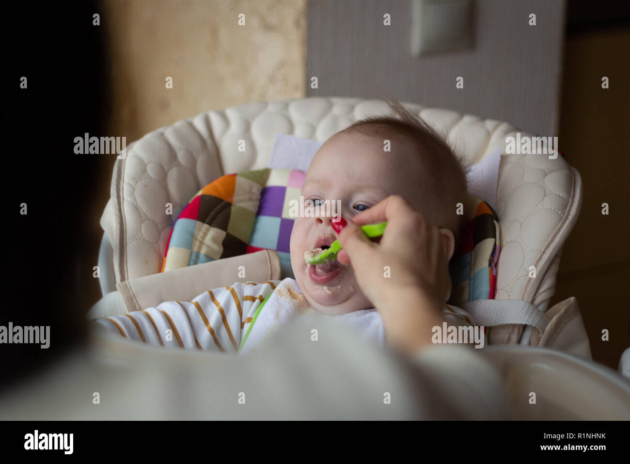 The first feeding of the baby from the spoon. Mom feeds baby ...