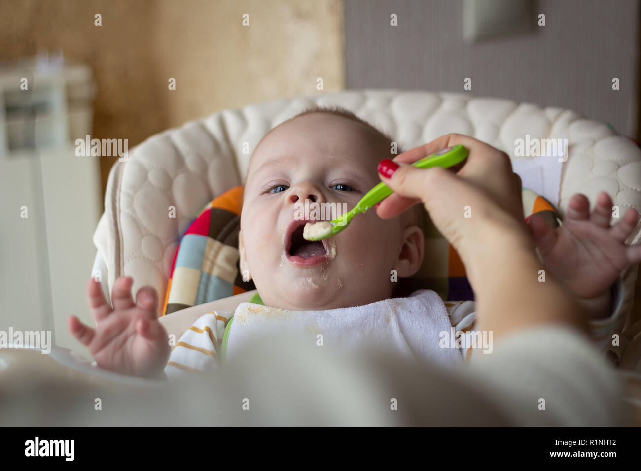 The first feeding of the baby from the spoon. Mom feeds baby ...