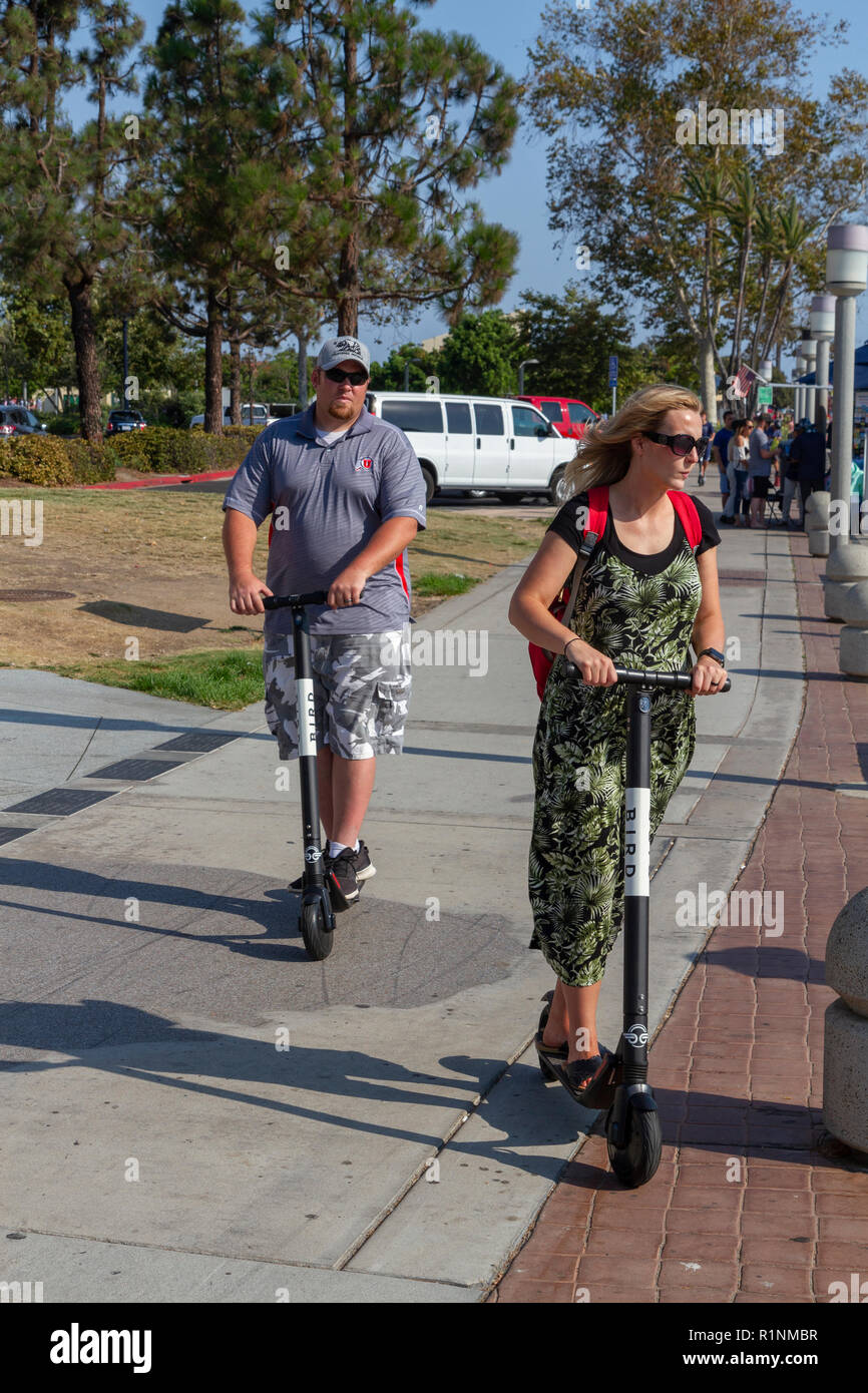 People on electric scooters riding on a footpath in San Diego ...