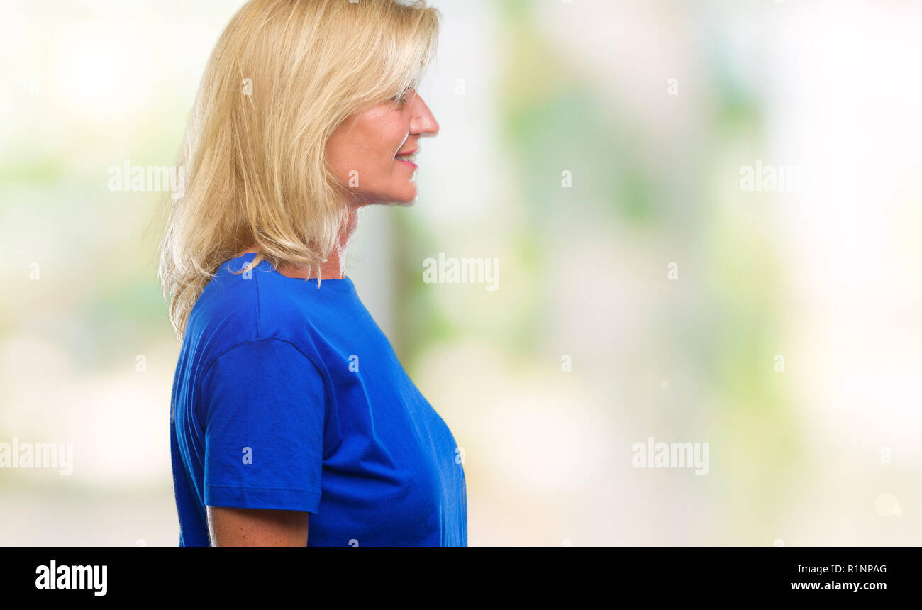 Middle age blonde woman over isolated background looking to side, relax profile pose with ...