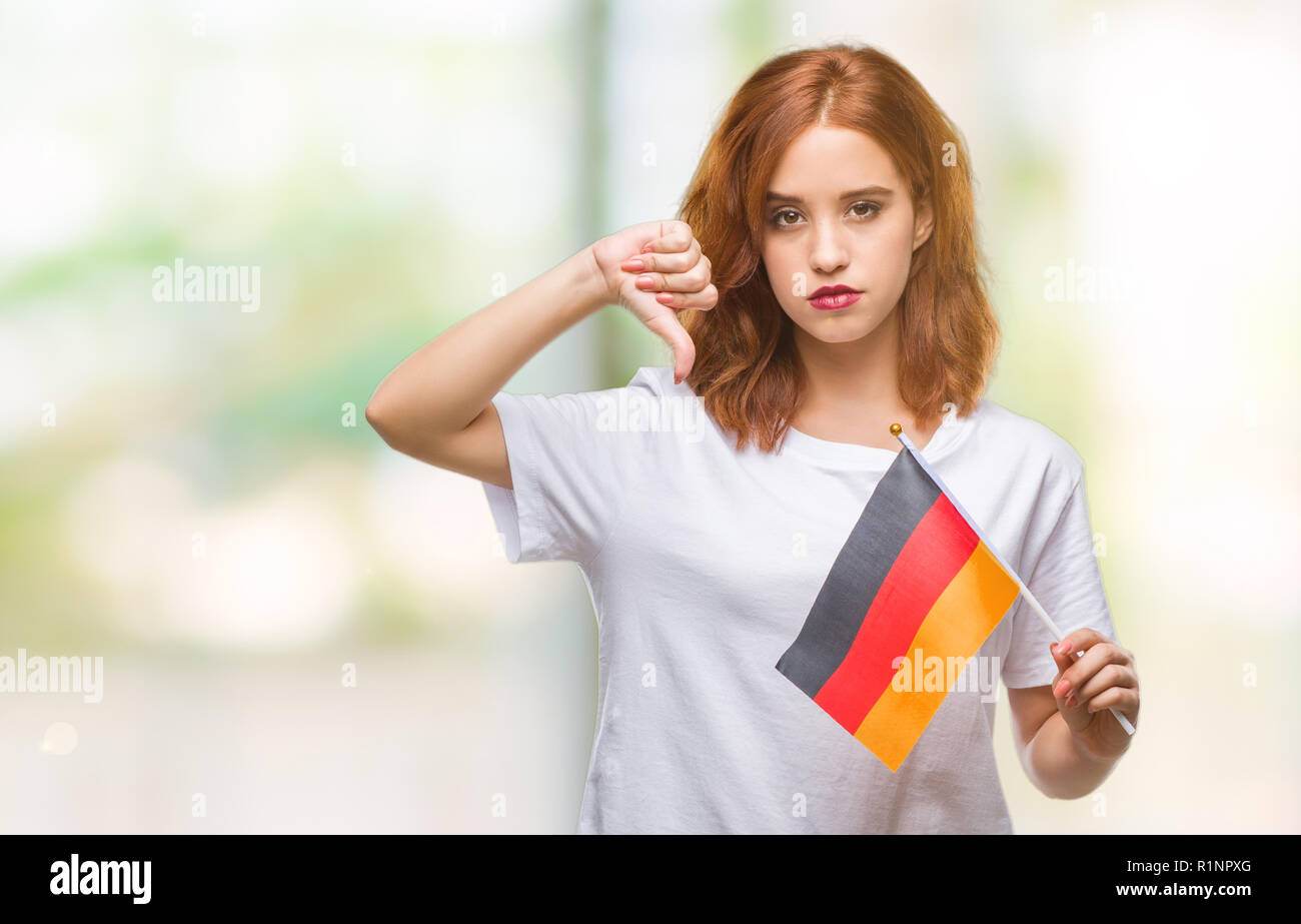 Young beautiful woman holding flag of germany over isolated background ...