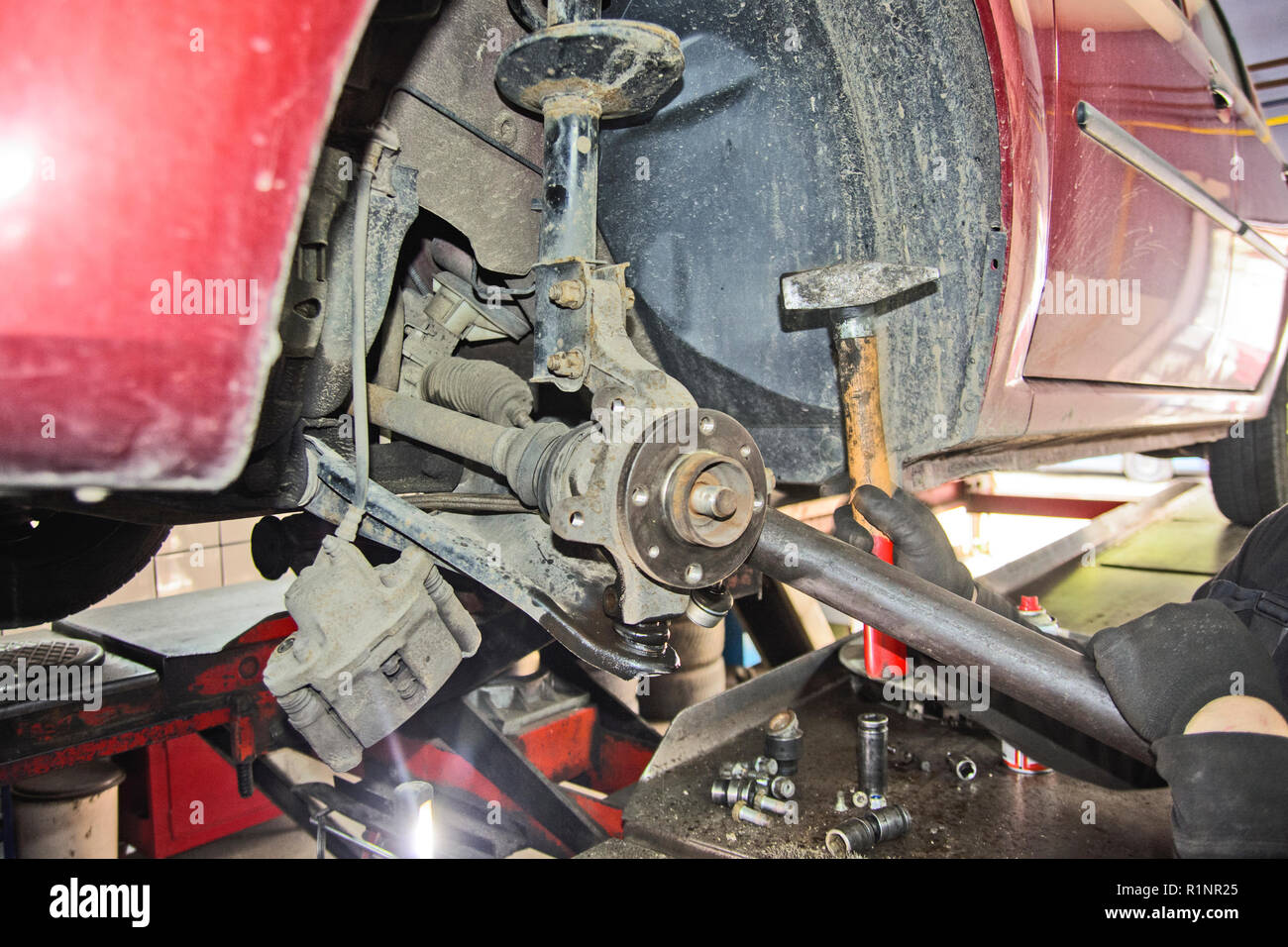 The mechanic in the workshop replaces the bearing on the front axle of ...