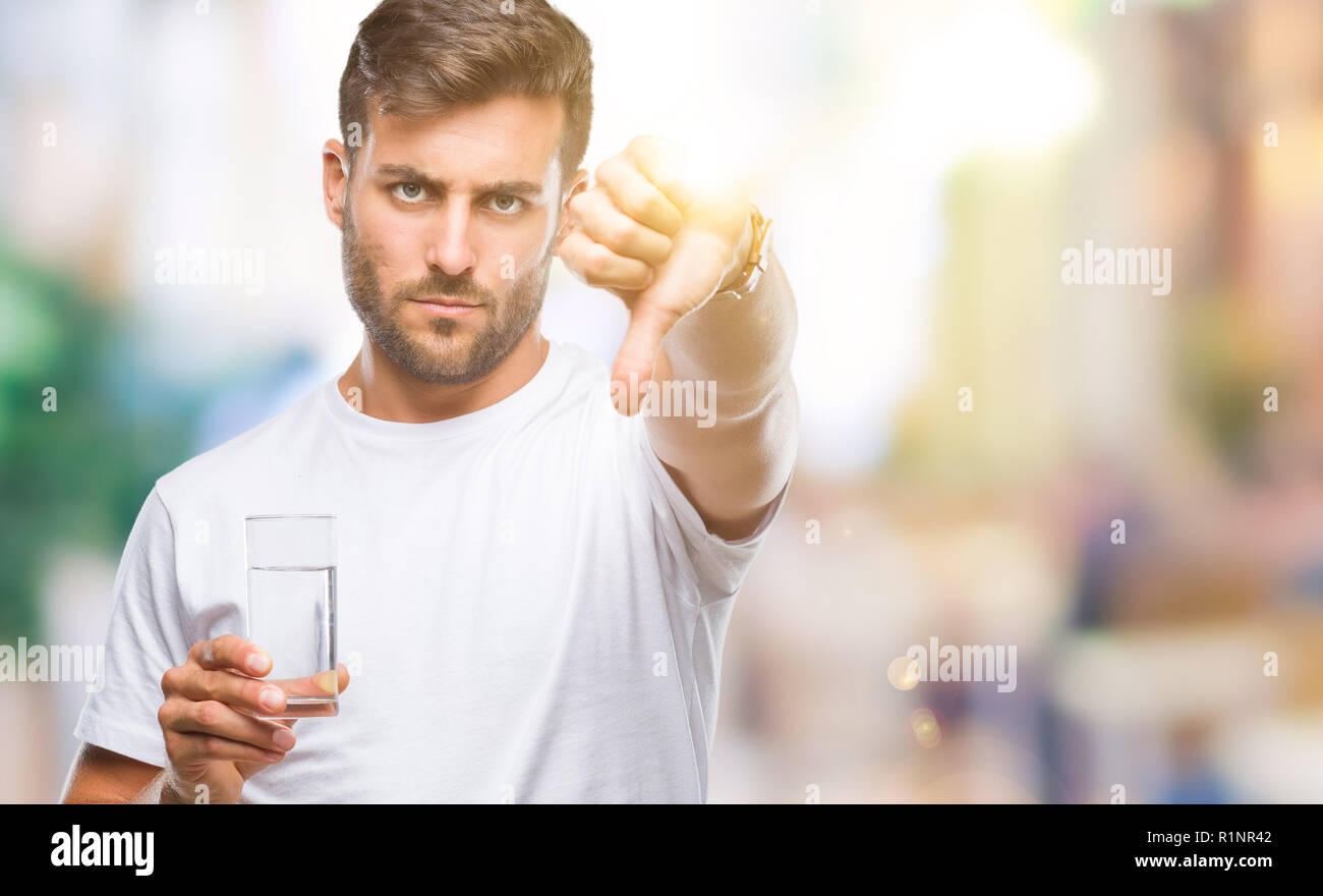 Young handsome man drinking glass of water over isolated background ...