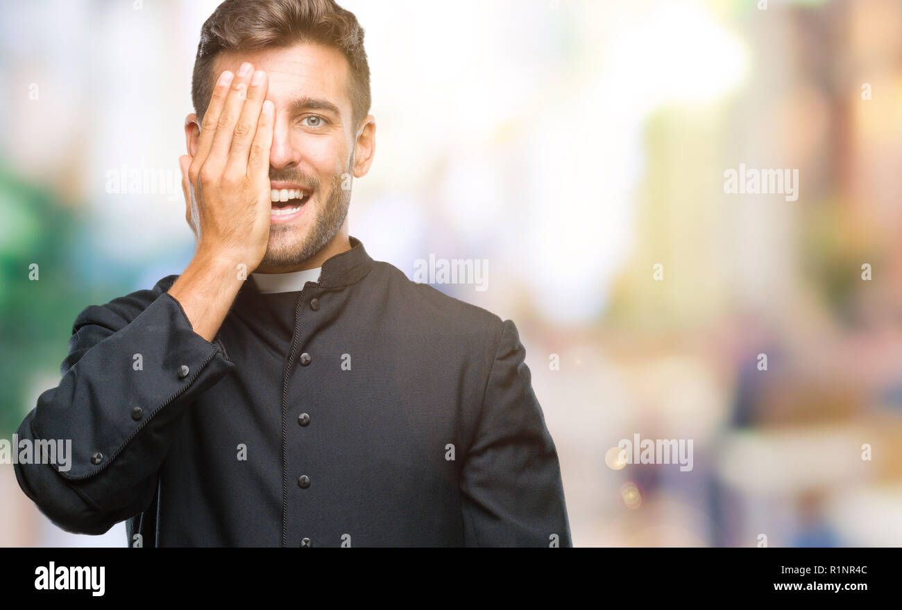 Young catholic christian priest man over isolated background covering ...