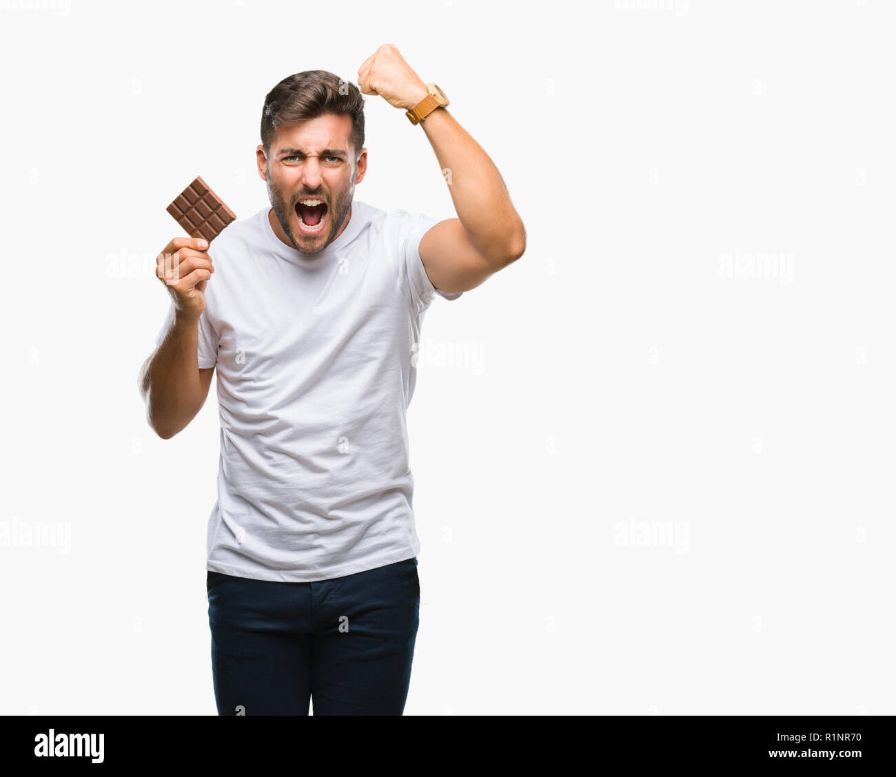 Young handsome man eating chocolate bar over isolated background ...