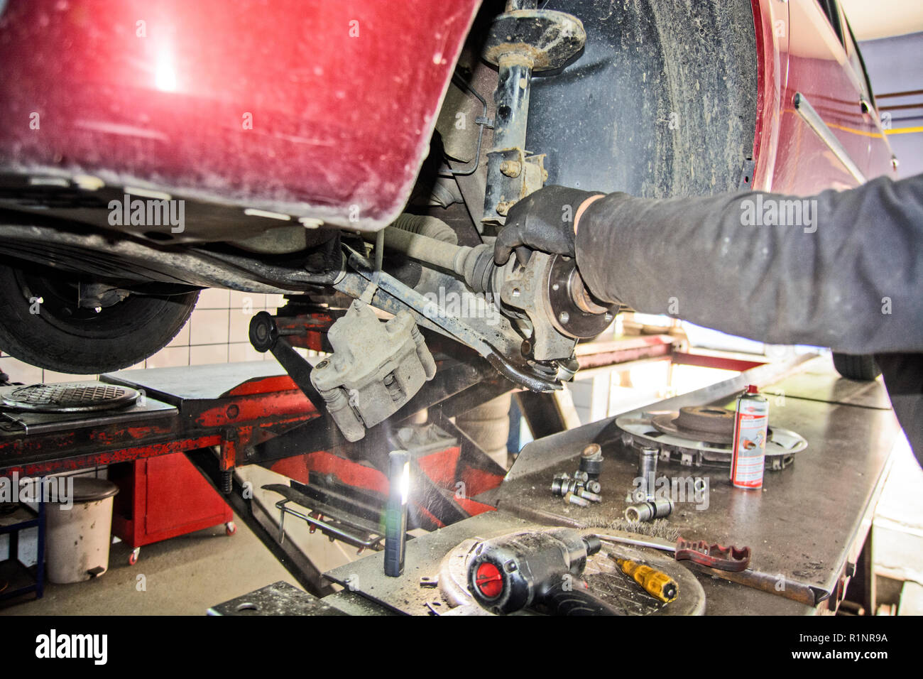 The mechanic in the workshop replaces the bearing on the front axle of ...