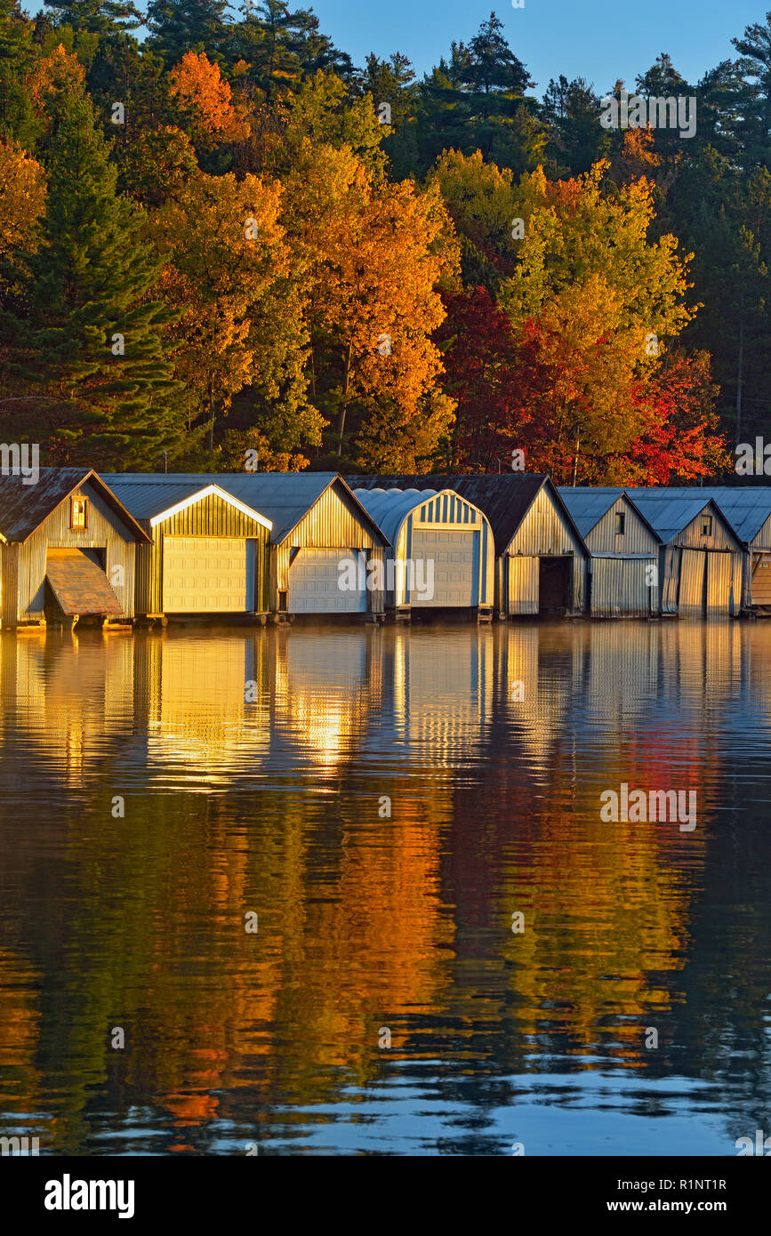 Boat houses reflected in the waters of Penage/Panache Lake at the ...