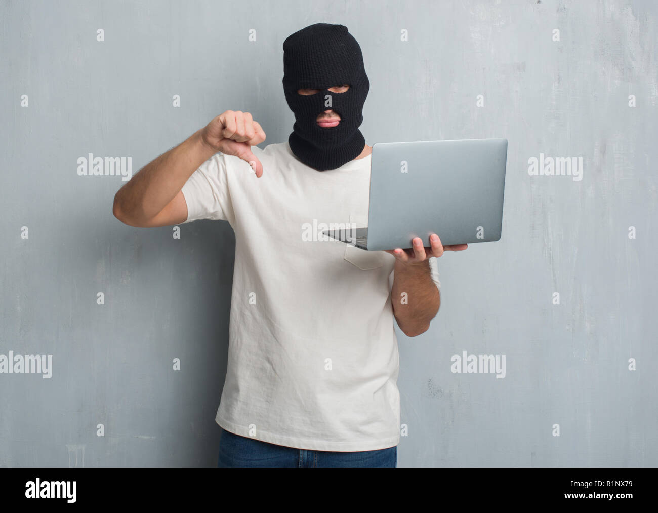 Young caucasian hacker man over grey grunge wall doing cyber attack ...